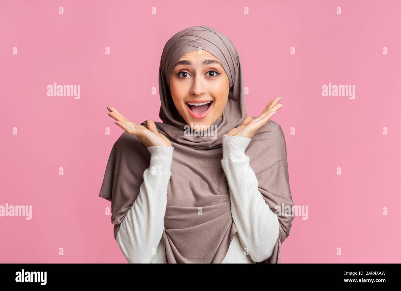 Portrait of excited young islamic girl in hijab exclaiming in amazement ...