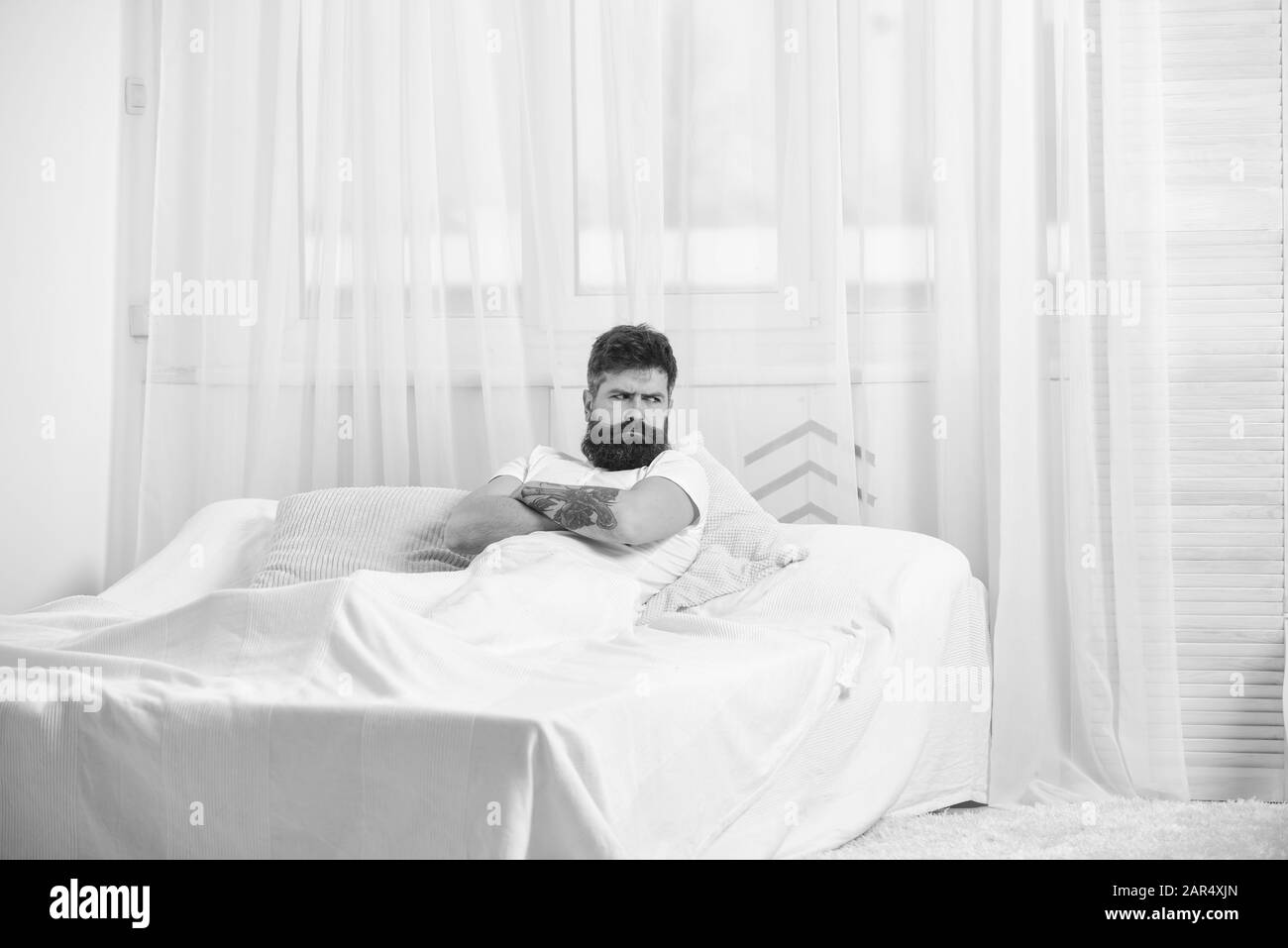 Guy on unhappy serious face looks angry in morning. Man in shirt laying ...