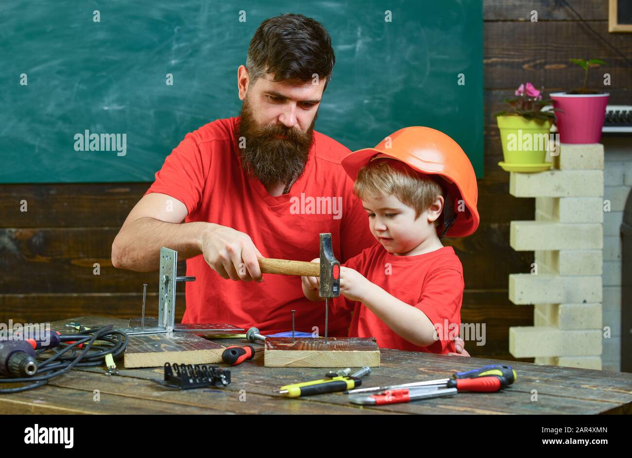Father with beard teaching little son to use tools, hammering ...