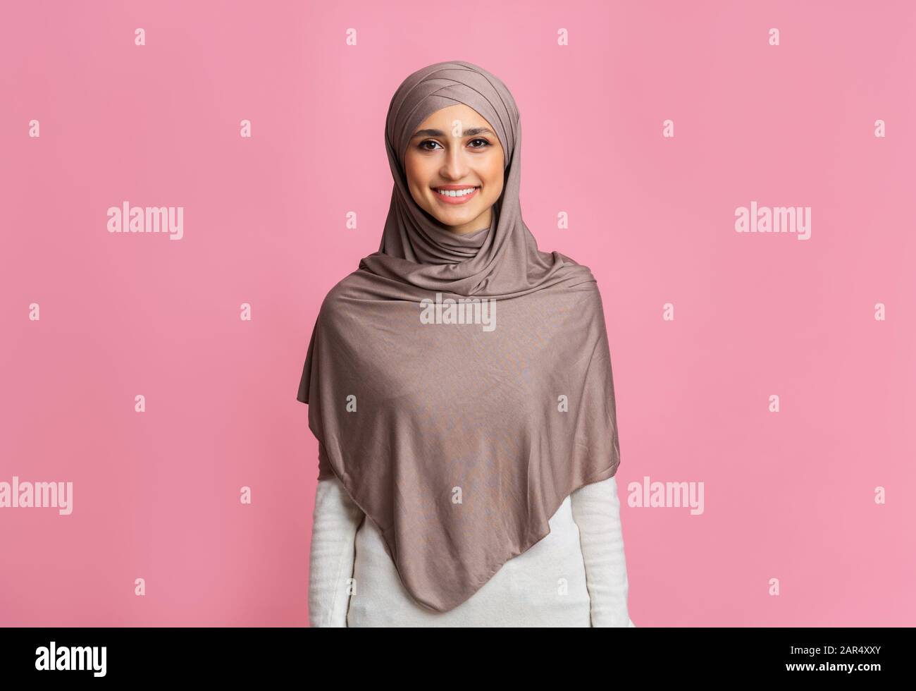 Portrait Of Beautiful Muslim Woman In Hijab Posing Over Pink Background