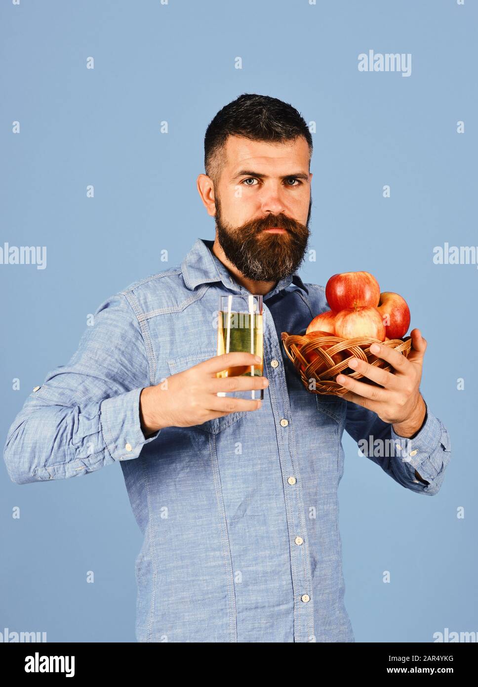 Man with beard holds bowl of fruit and juice isolated on blue ...