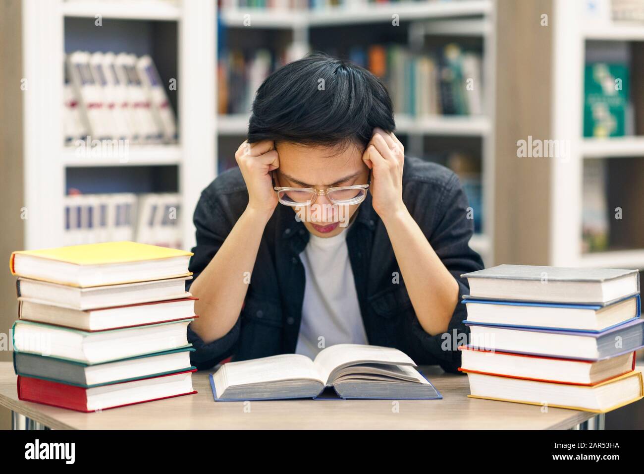 Stressed chinese guy preparing for examination in library Stock Photo ...