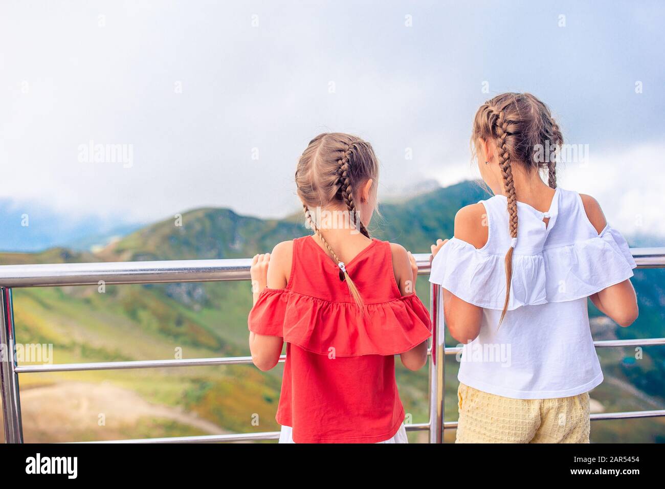 Back view of friendly little girls in mountains in the background of ...