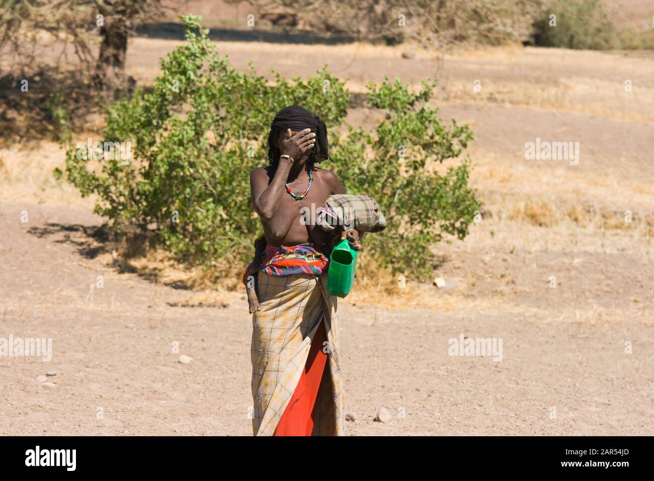 A Afar woman with a child on her back covers her face, Afar Region ...