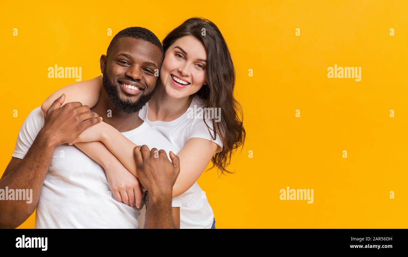 Portrait of happy multiracial couple embracing, posing together over ...