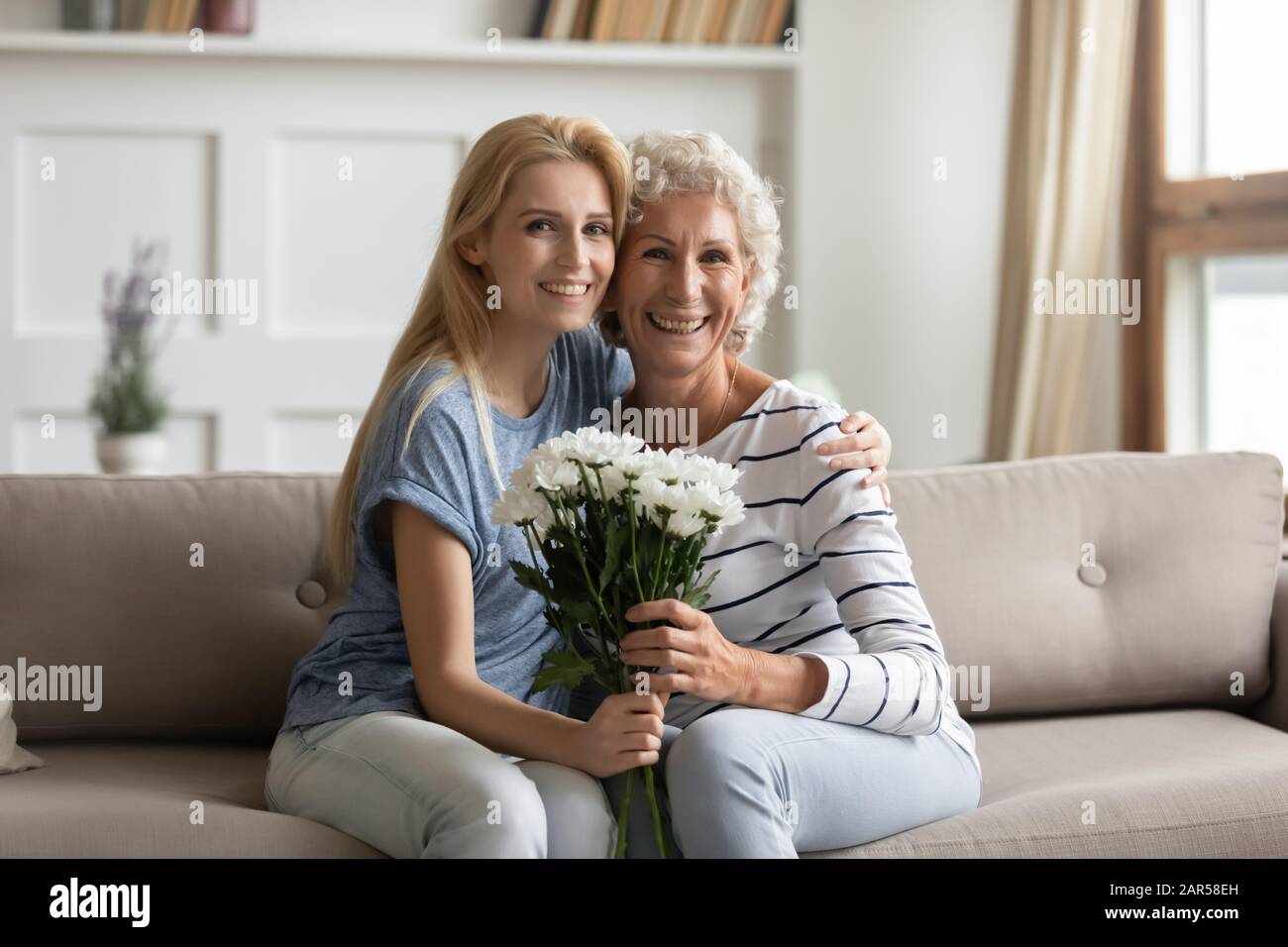 Portrait of young grown up daughter embracing middle aged mother Stock Photo - Alamy