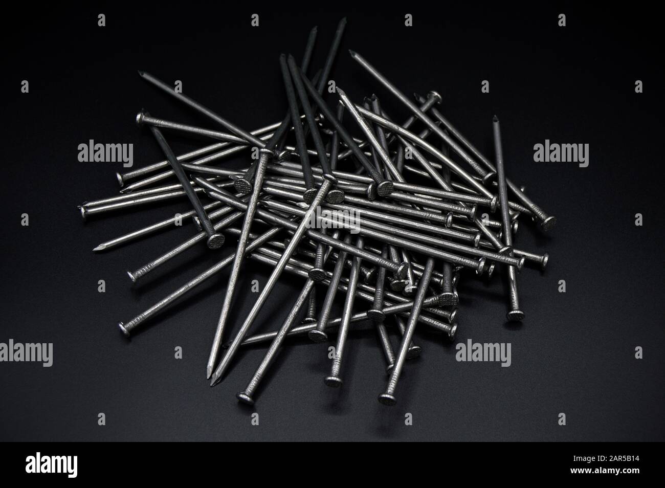 A lot of construction iron nails, industrial parts, isolated on black ...