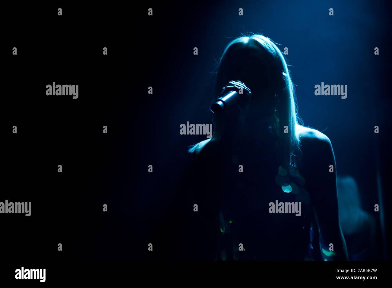 silhouette of long-haired singer in blue spotlight on stage Stock Photo ...