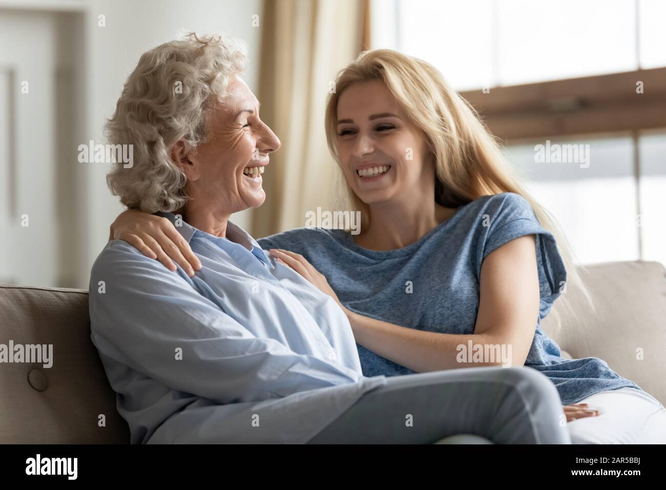 Happy young woman embracing shoulders of excited middle aged mother ...