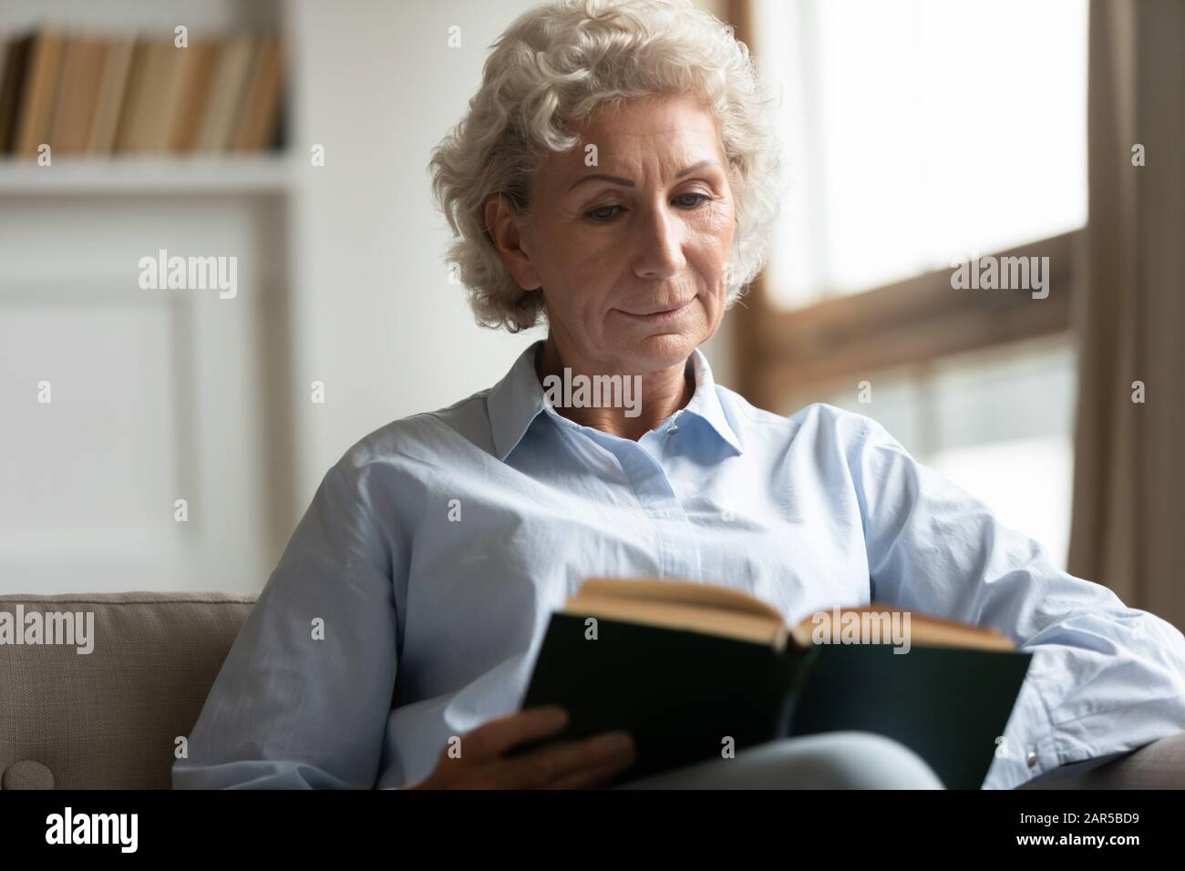 Peaceful older woman reading interesting bestseller paper book Stock ...