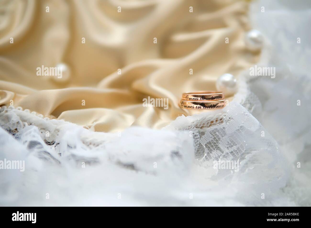wedding rings with inscriptions in Latin lie on a two-color silk fabric ...