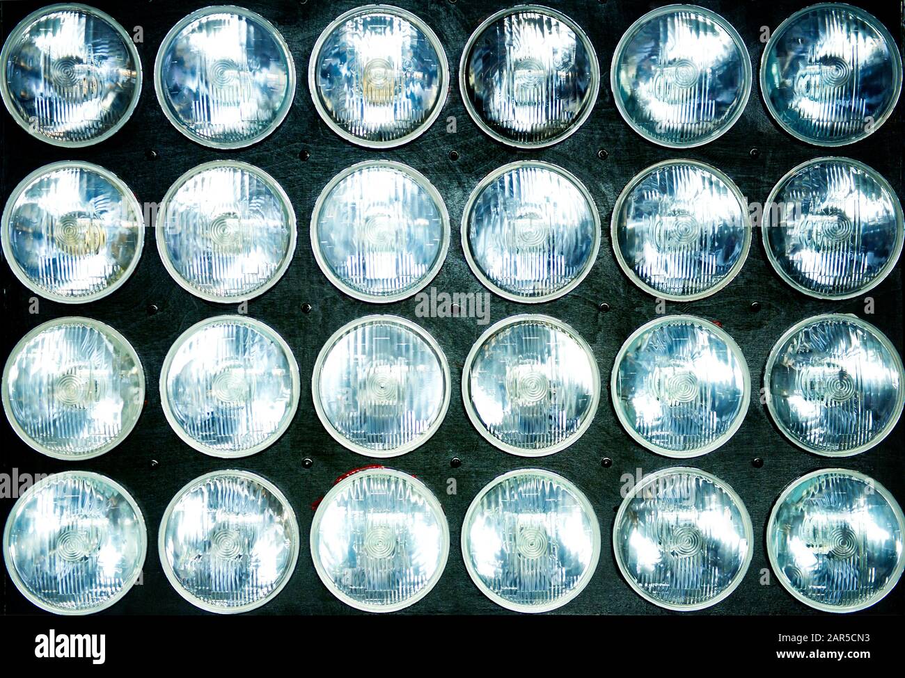 wooden panel with a large number of round headlights installed in it ...