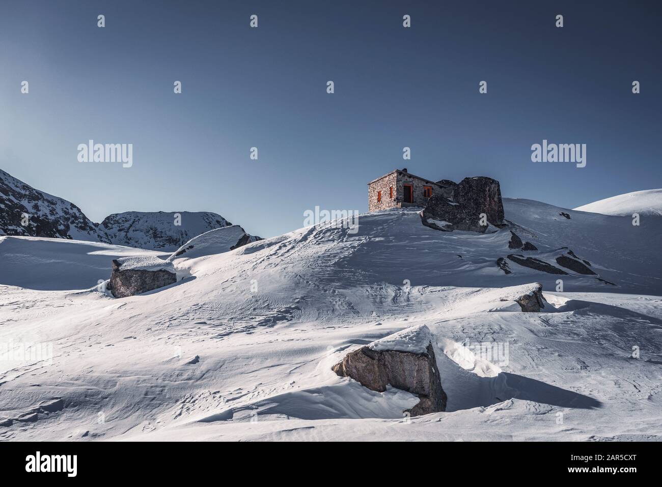 Ice and snow covered small stone shelter hut, standing on top of the ...