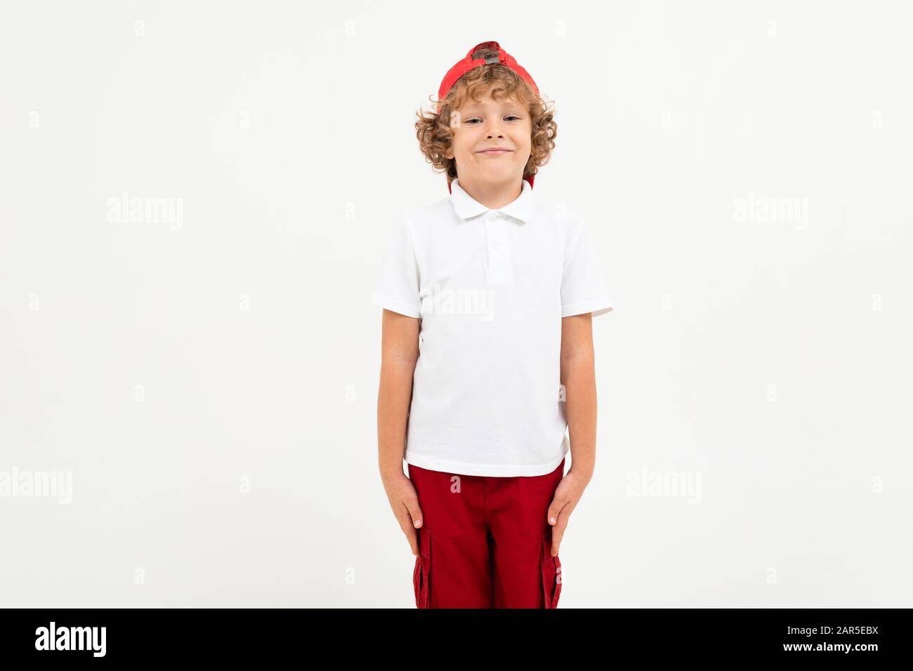 Caucasian boy in white t-shirt, red cap, red shorts smiles isolated on ...