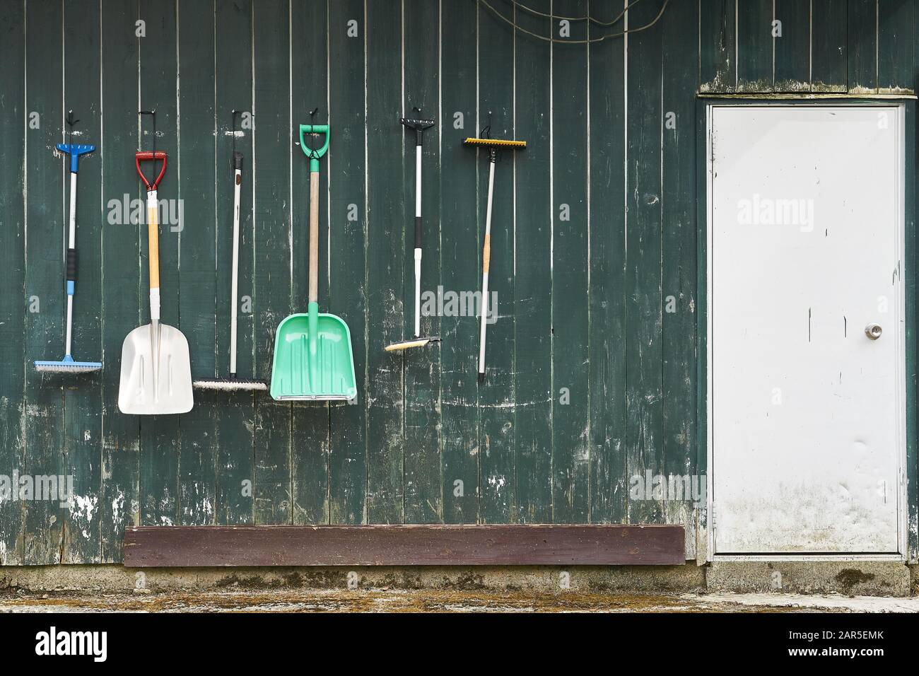Winter tools like snow shovels, ice scrapers, and snow brushes hang ...