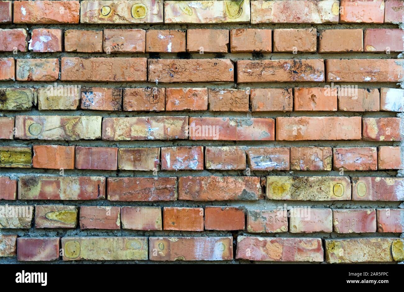 A wall of bricks, roughly laid out with heterogeneous spots and cracked ...