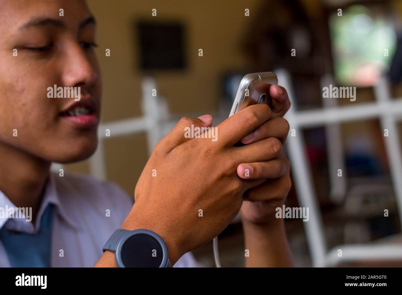 Indonesian student playing on his phone Stock Photo - Alamy