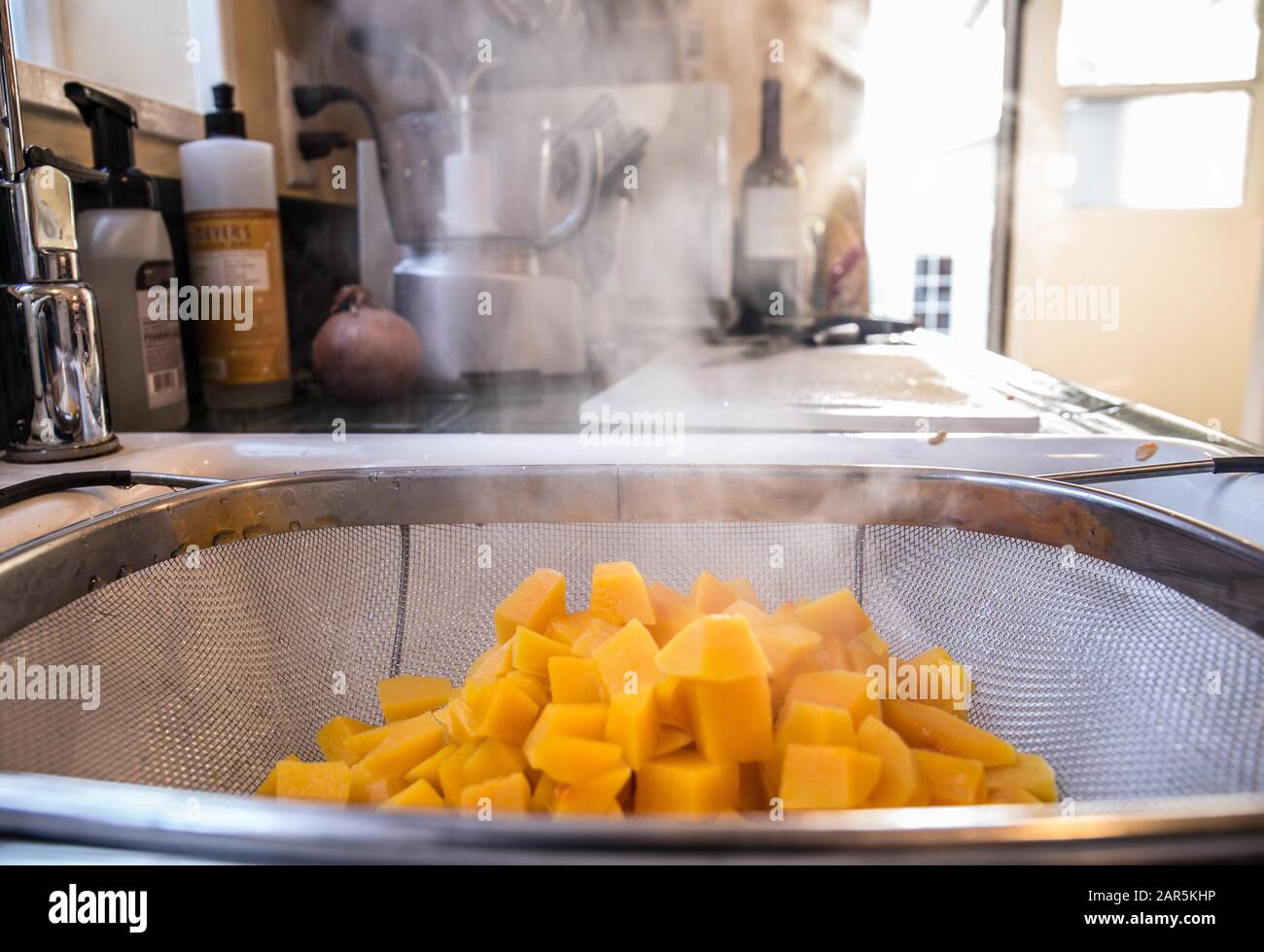 Peeled and square-shaped cuts of hot mango in a metal strainer in the ...