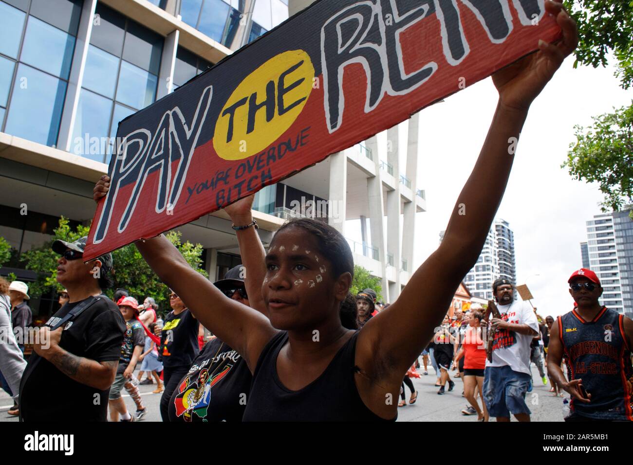A woman holds a placard during the rally.Indigenous Yuggera and Turrbal ...