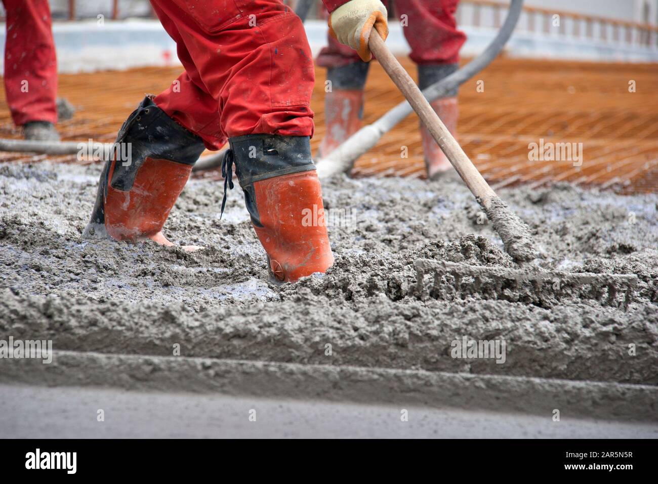 Group of construction workers spreading freshly poured concrete mix on ...