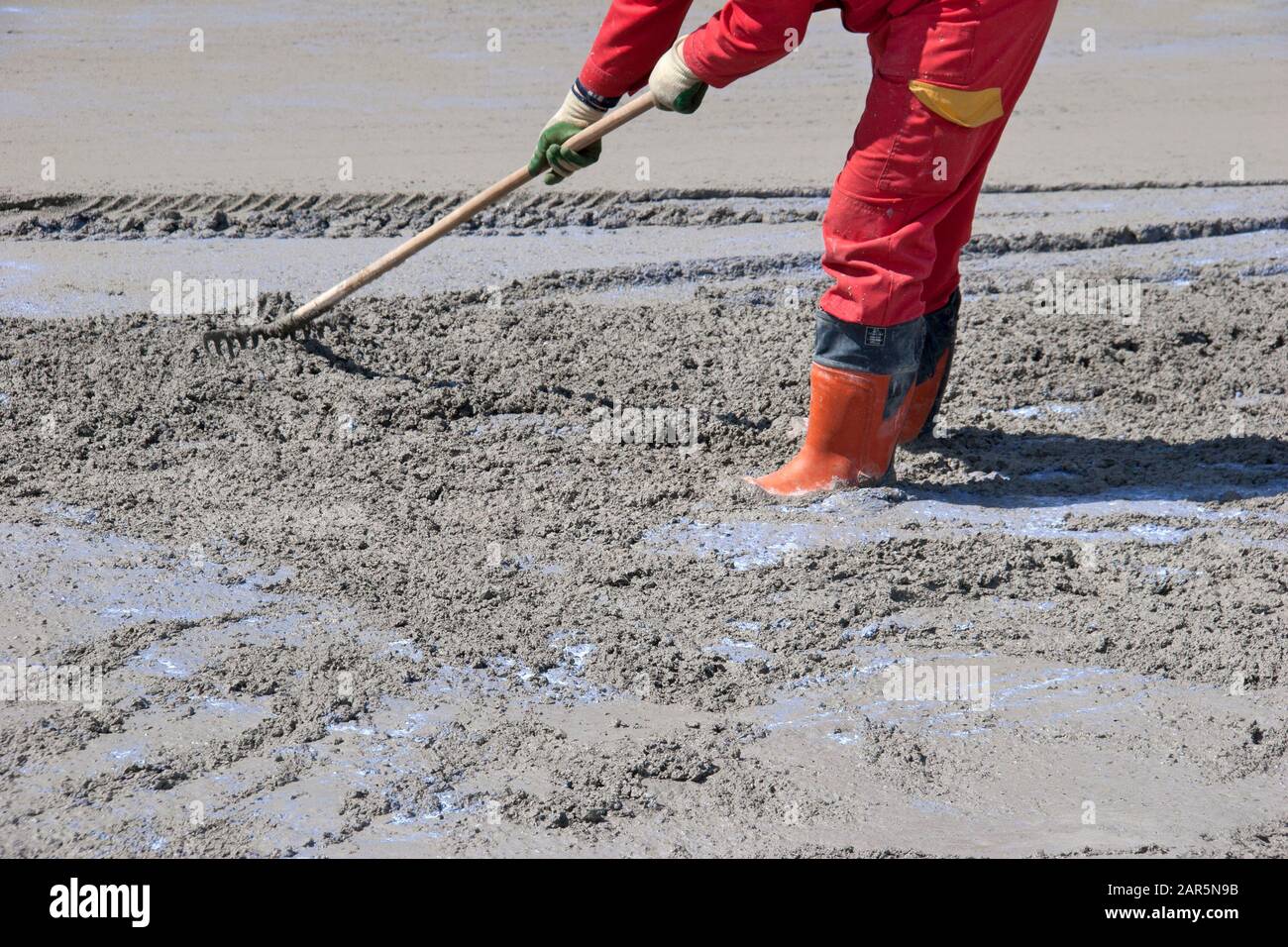 Construction worker spreading freshly poured concrete mix on the bridge ...