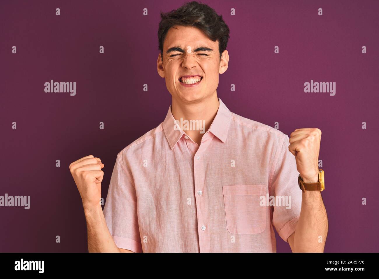 Teenager boy wearing pink shirt standing over purple isolated ...