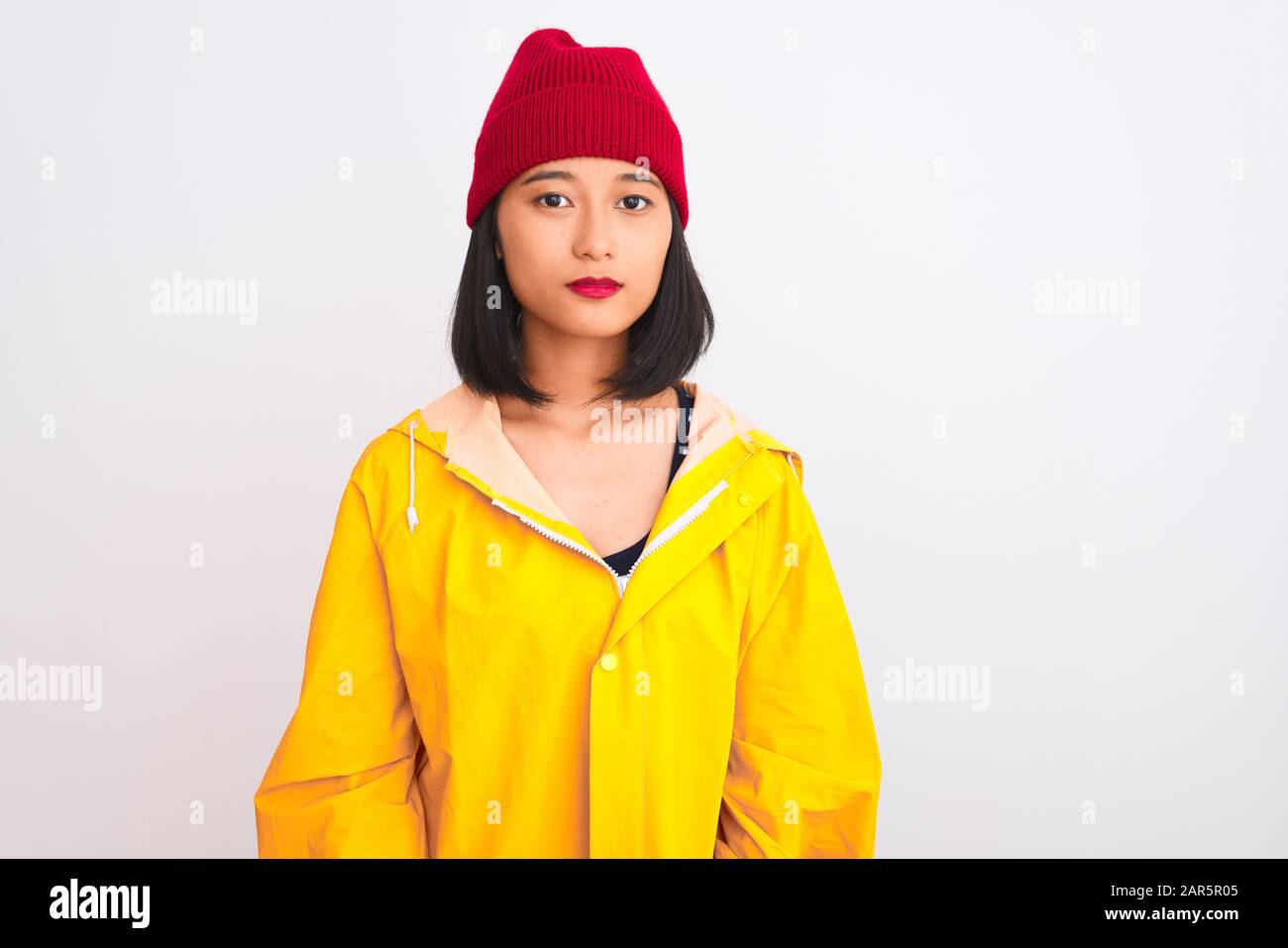 Young beautiful chinese woman wearing raincoat and wool cap over ...