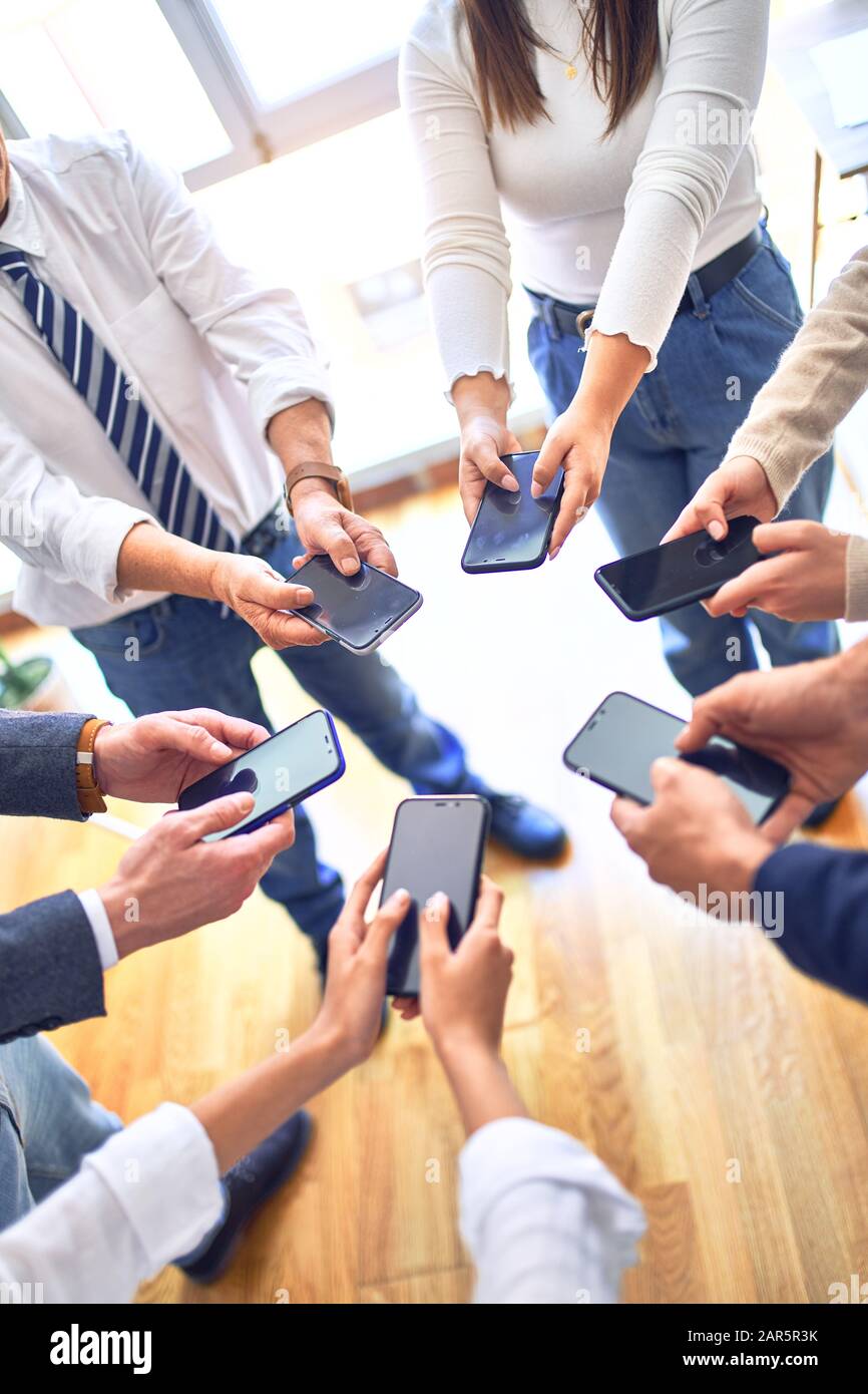 Group of business workers standing with hands together using smartphone ...