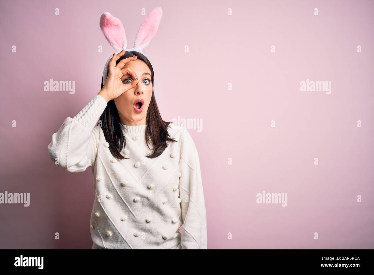 Young caucasian woman wearing cute easter rabbit ears over pink ...