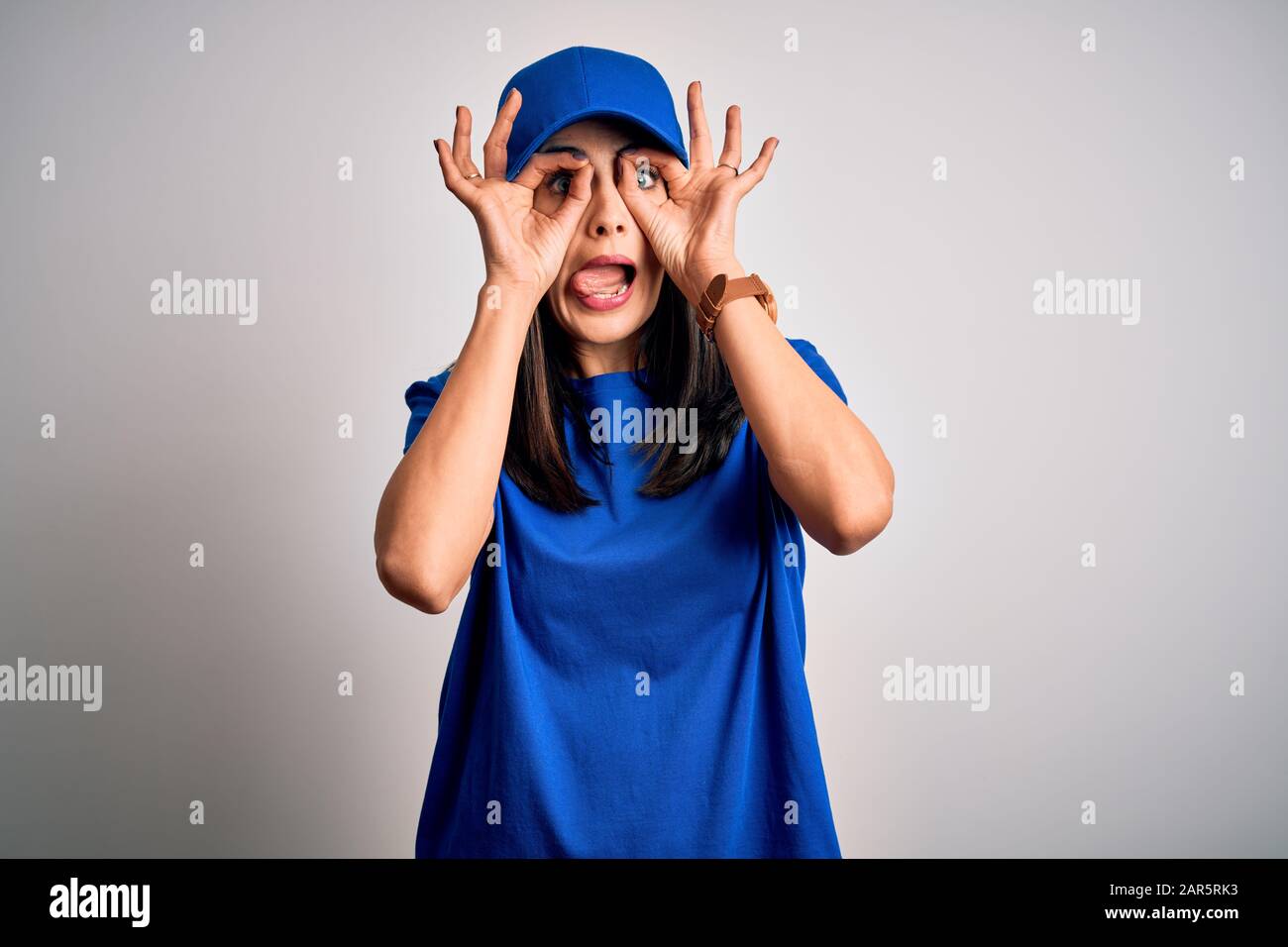 Young delivery woman with blue eyes wearing cap standing over blue ...