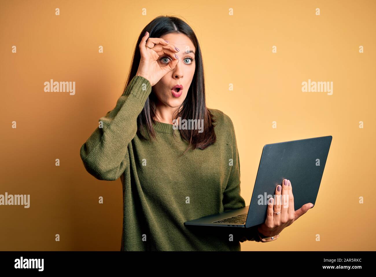 Young brunette woman with blue eyes working using computer laptop over ...