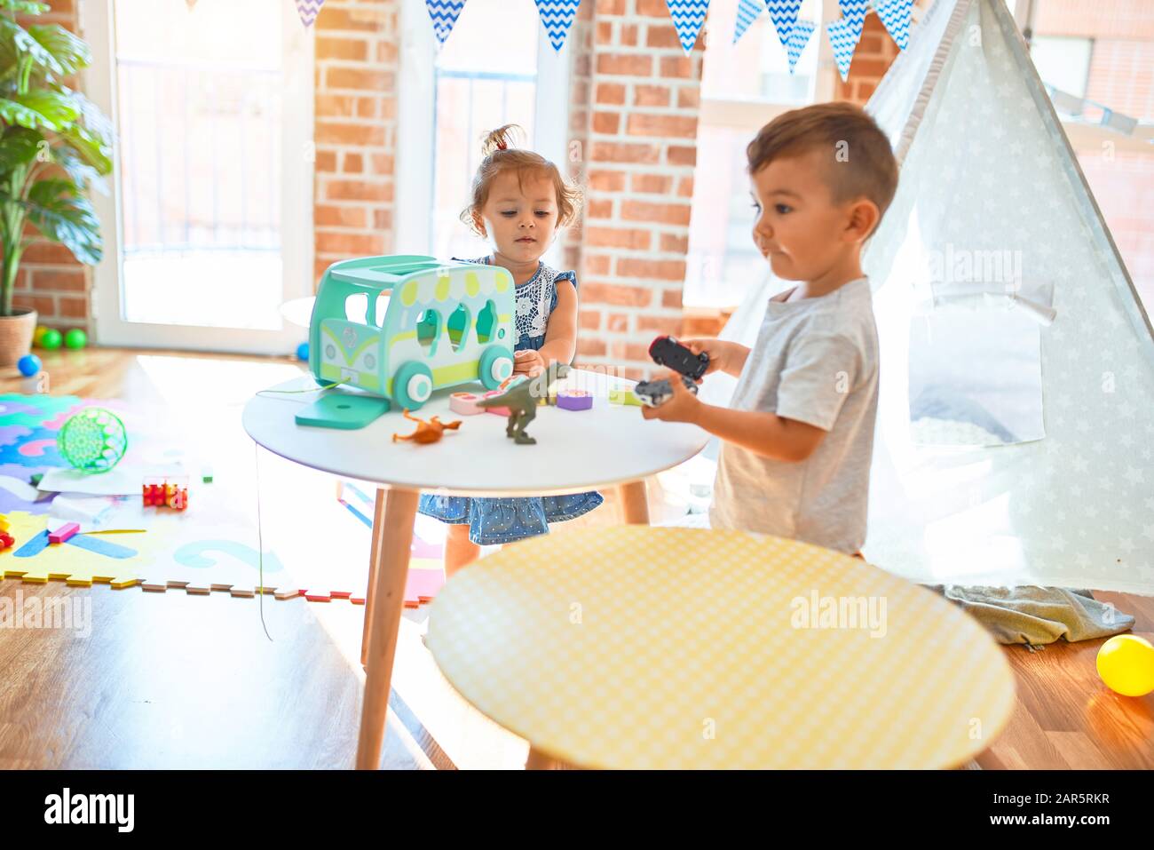 Adorable toddlers smiling happy. Standing playing around lots of toys ...