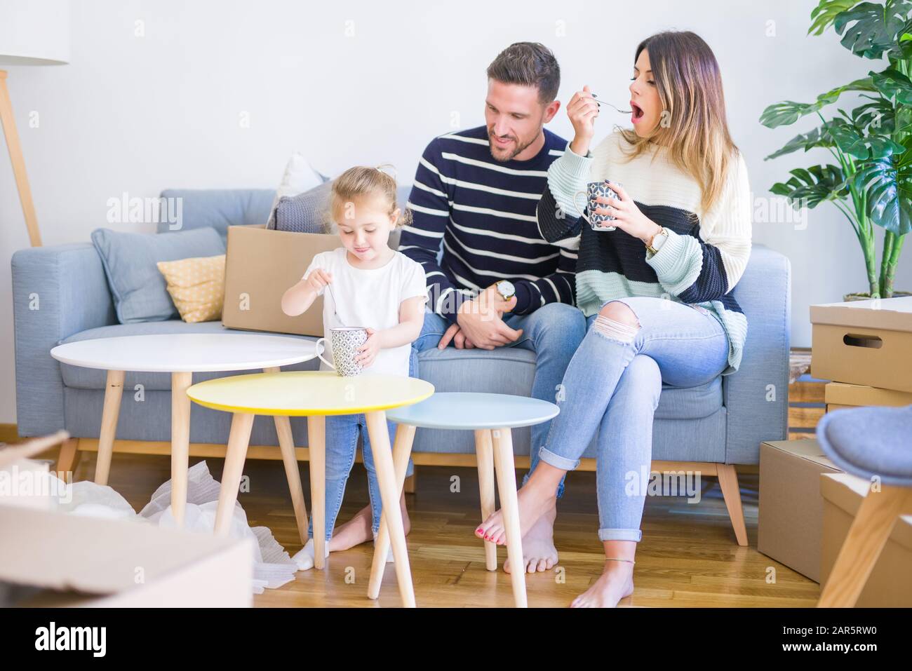 Beautiful family, parents sitting on the sofa drinking coffee looking ...