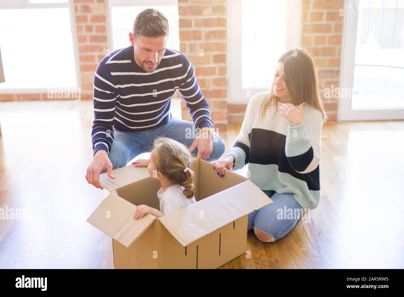 Beautiful famiily, kid playing with his parents riding cardboard fanny ...