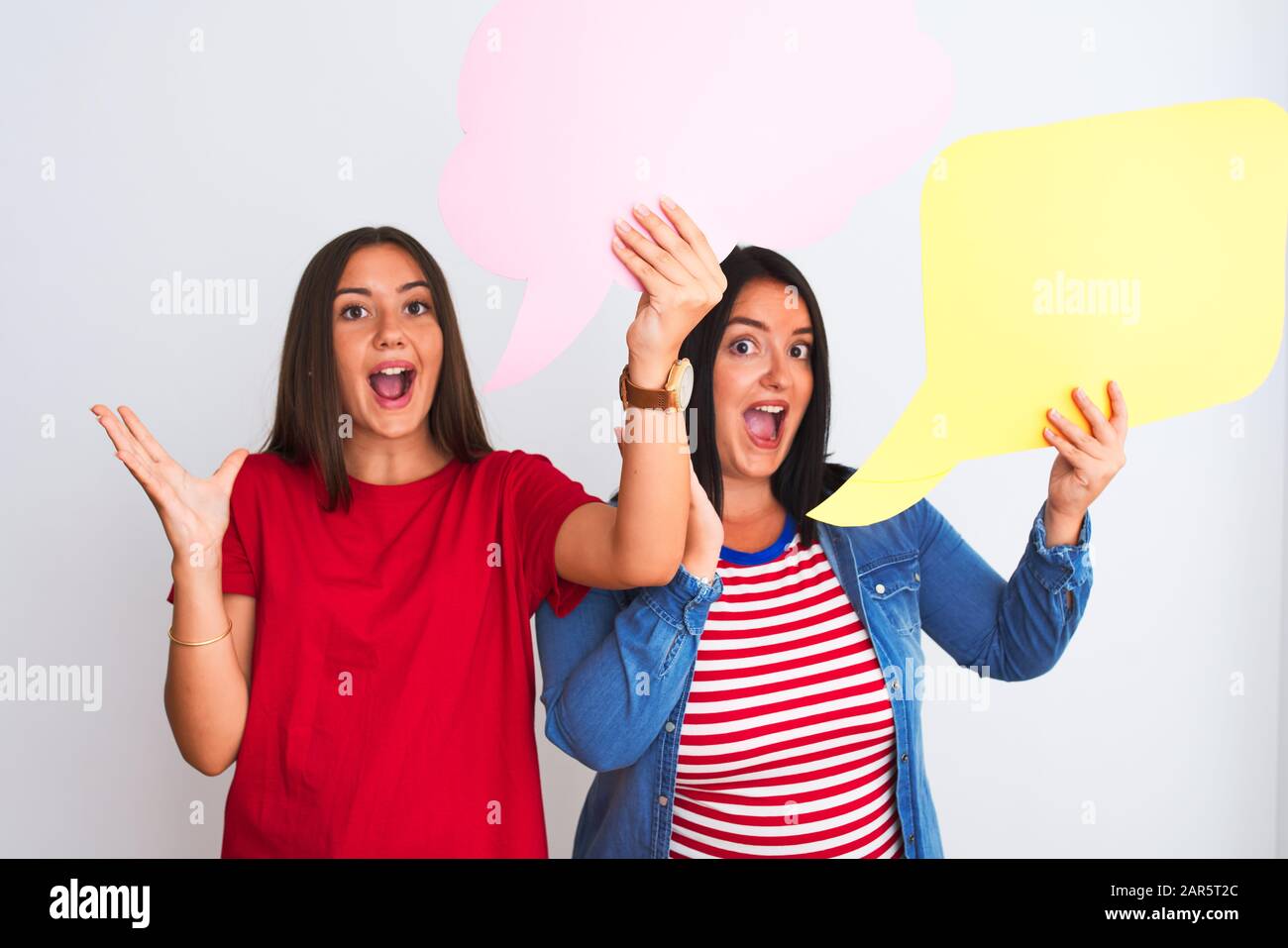 Young beautiful women holding speech bubble standing over isolated ...