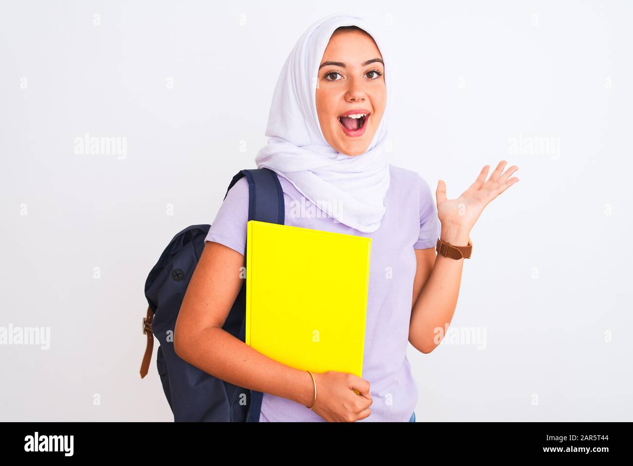 Arab student girl wearing hijab and backpack holding book over isolated ...