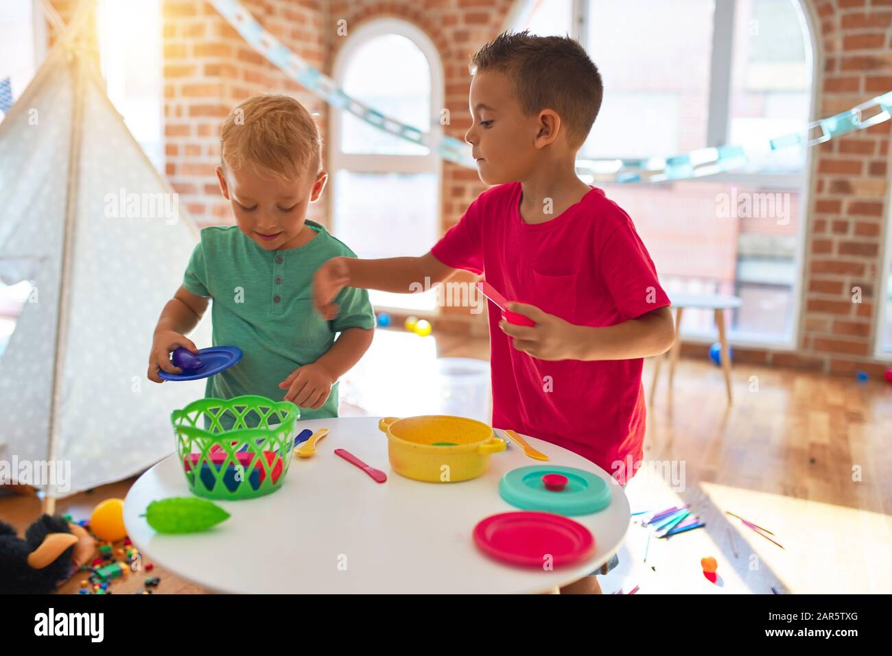 Adorable toddlers playing around lots of toys at kindergarten Stock ...