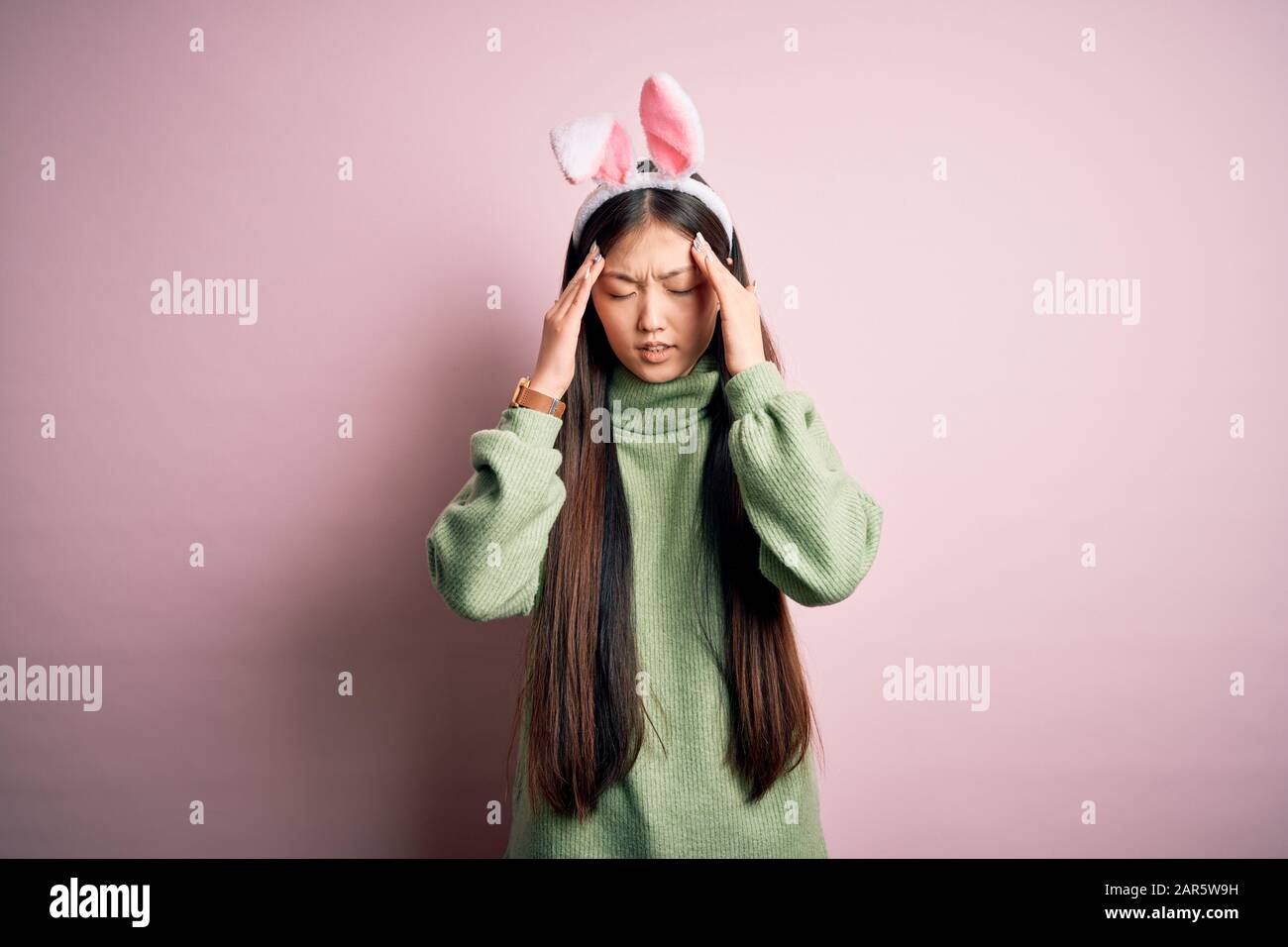 Young asian woman wearing cute easter bunny ears over pink background ...