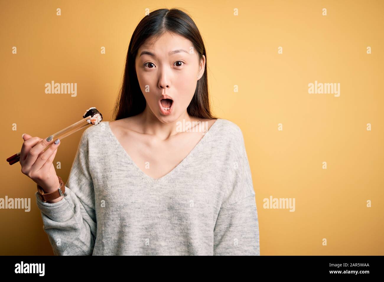 Young asian woman eating japanese food, holding salmon and rice maki ...