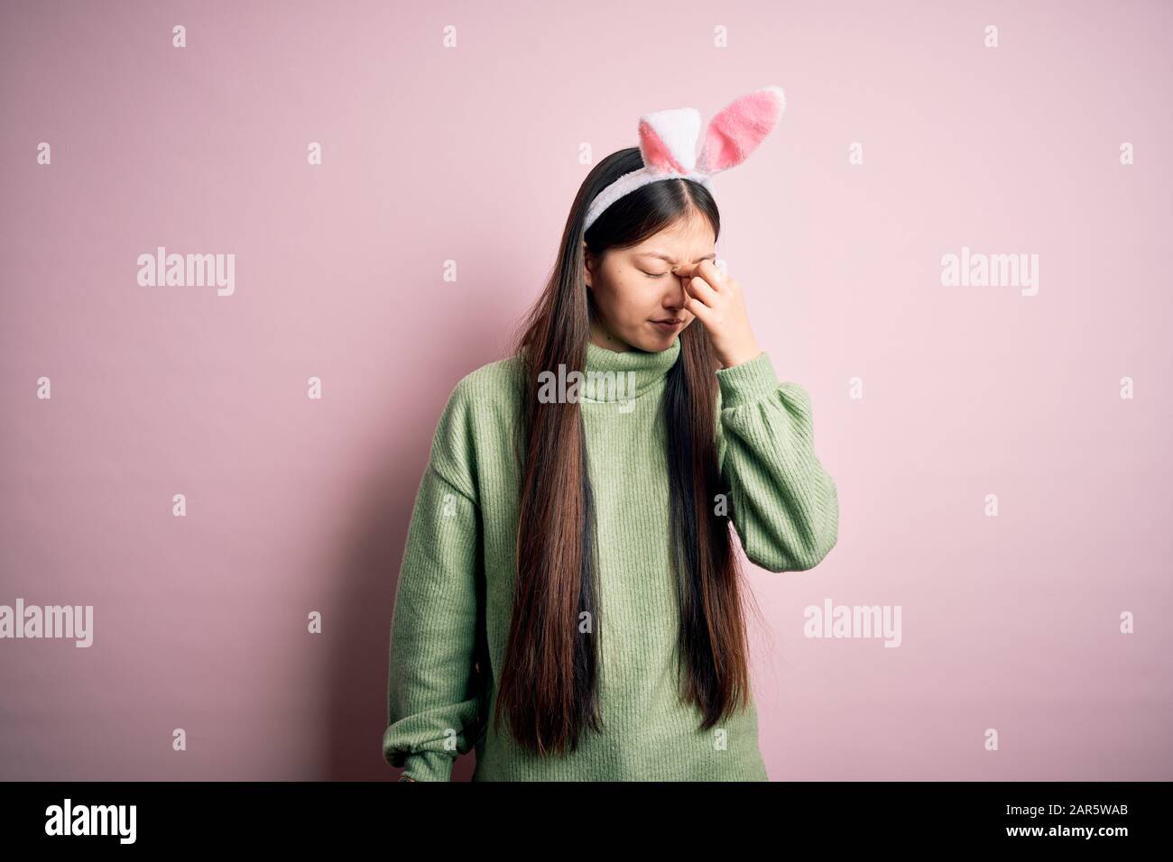Young asian woman wearing cute easter bunny ears over pink background ...