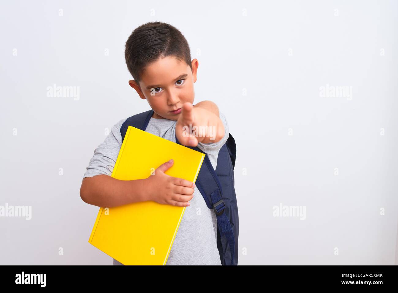 Beautiful student kid boy wearing backpack holding book over isolated ...