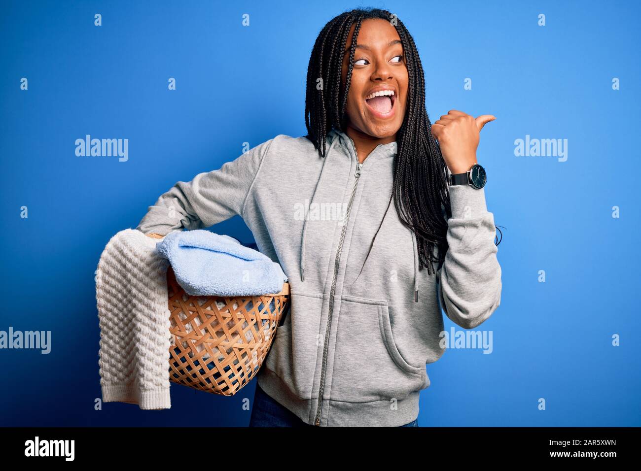 Young african american girl doing domestic housework holding laundry ...