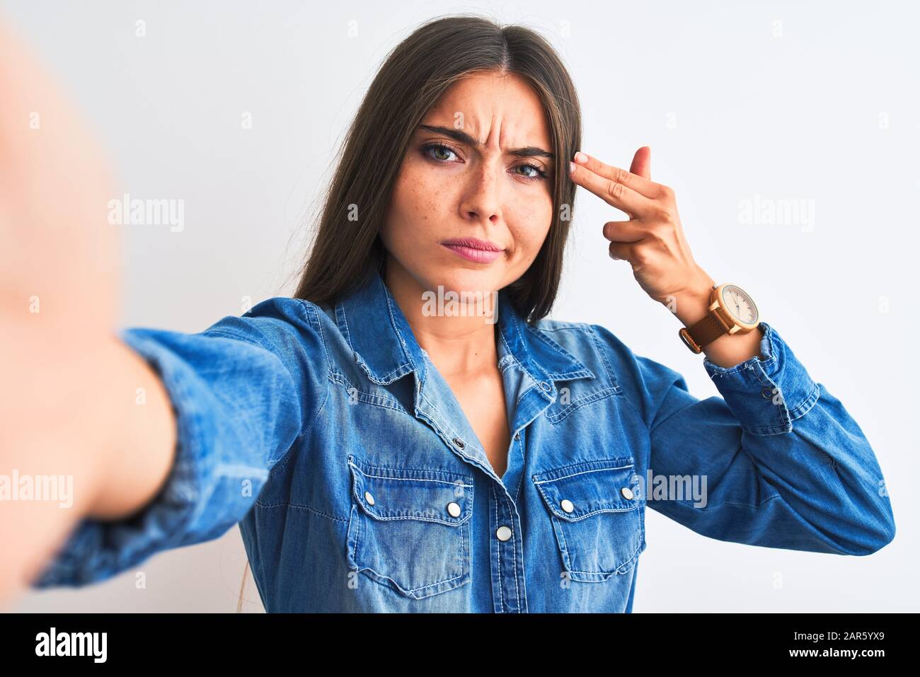 Beautiful woman wearing denim shirt make selfie by camera over isolated ...