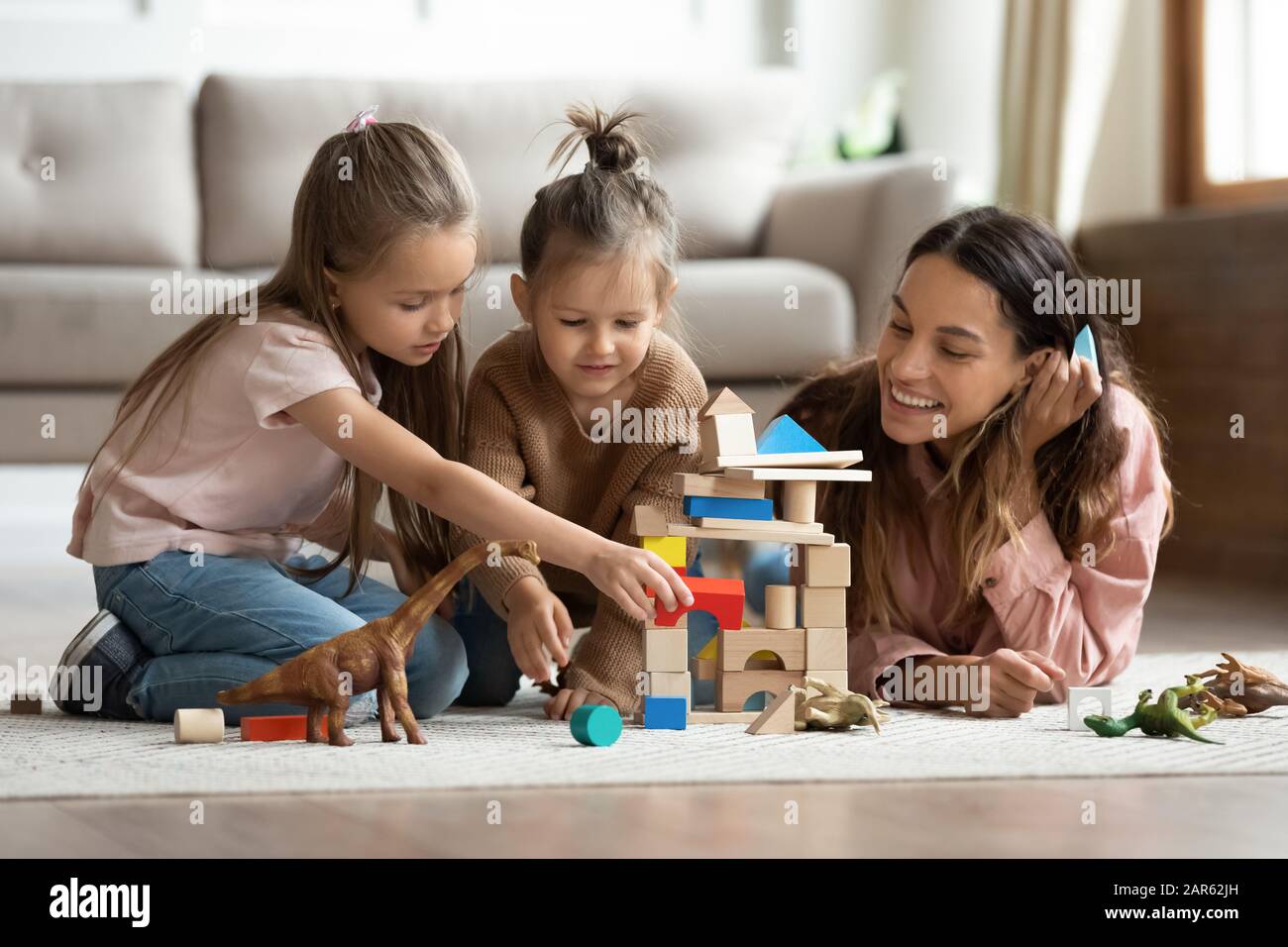 Young mom playing with building bricks with little daughters Stock ...