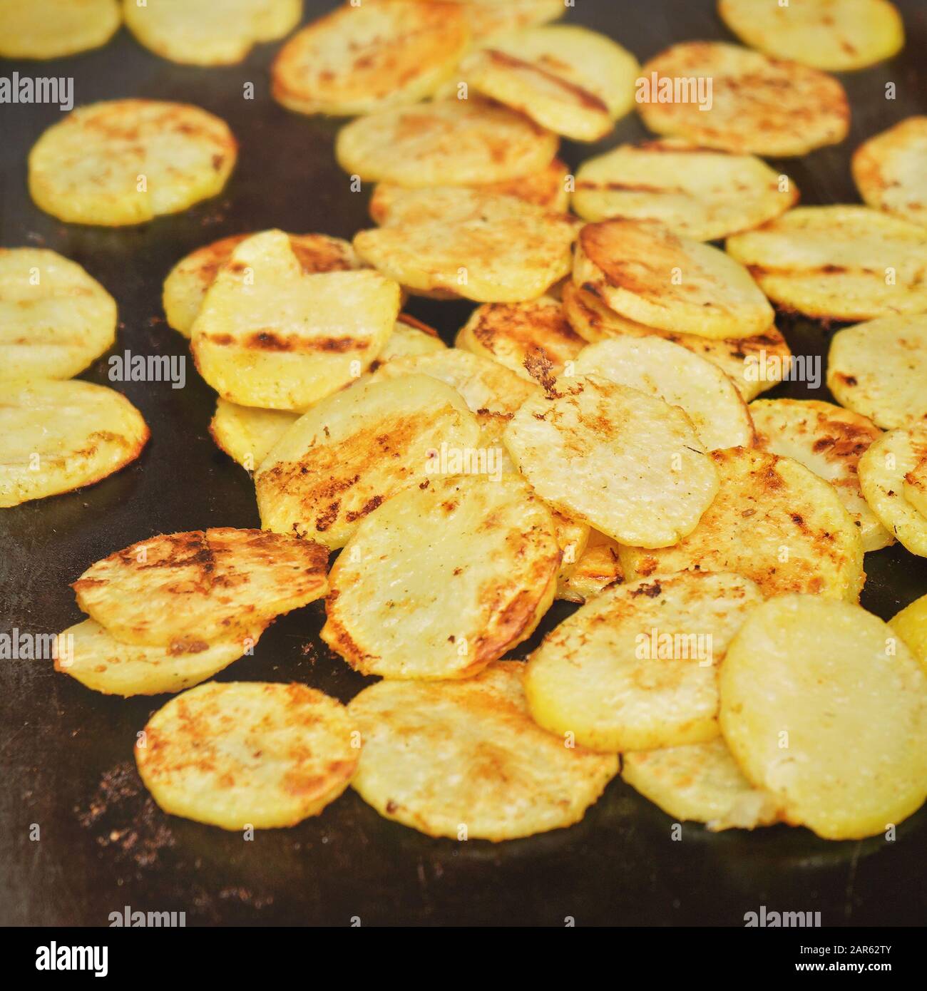 Potato chips seasoned with spices grilled on electric grill, closeup ...