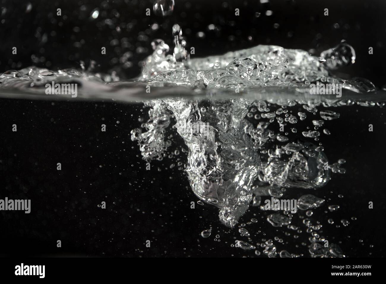 Water splashing as it's poured into aquarium tank, black background ...