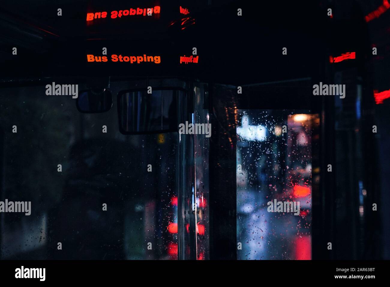 Bus stopping sign flashing in the public transport on rainy evening ...