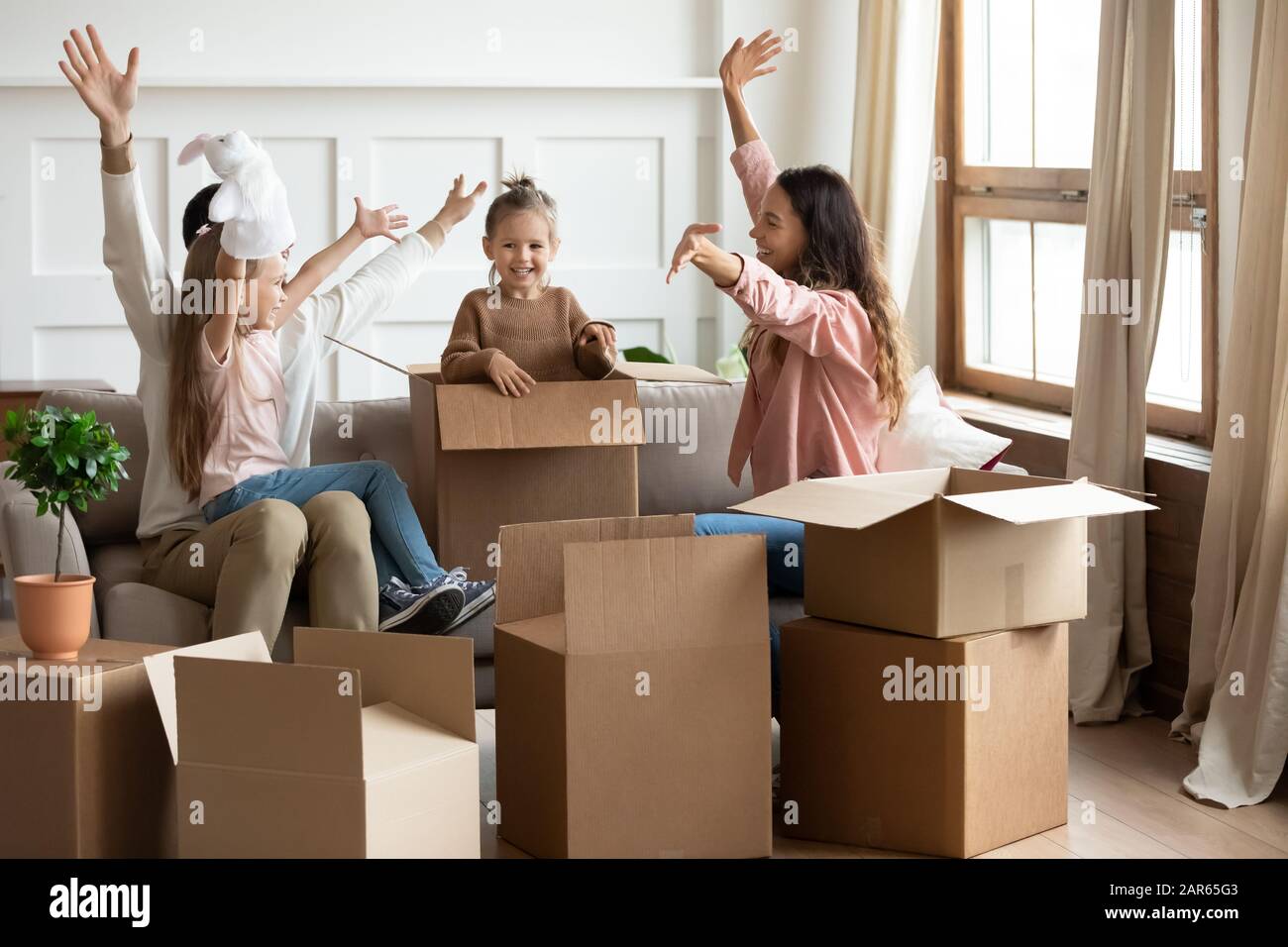 Overjoyed young parents play with little kids on moving day Stock Photo ...