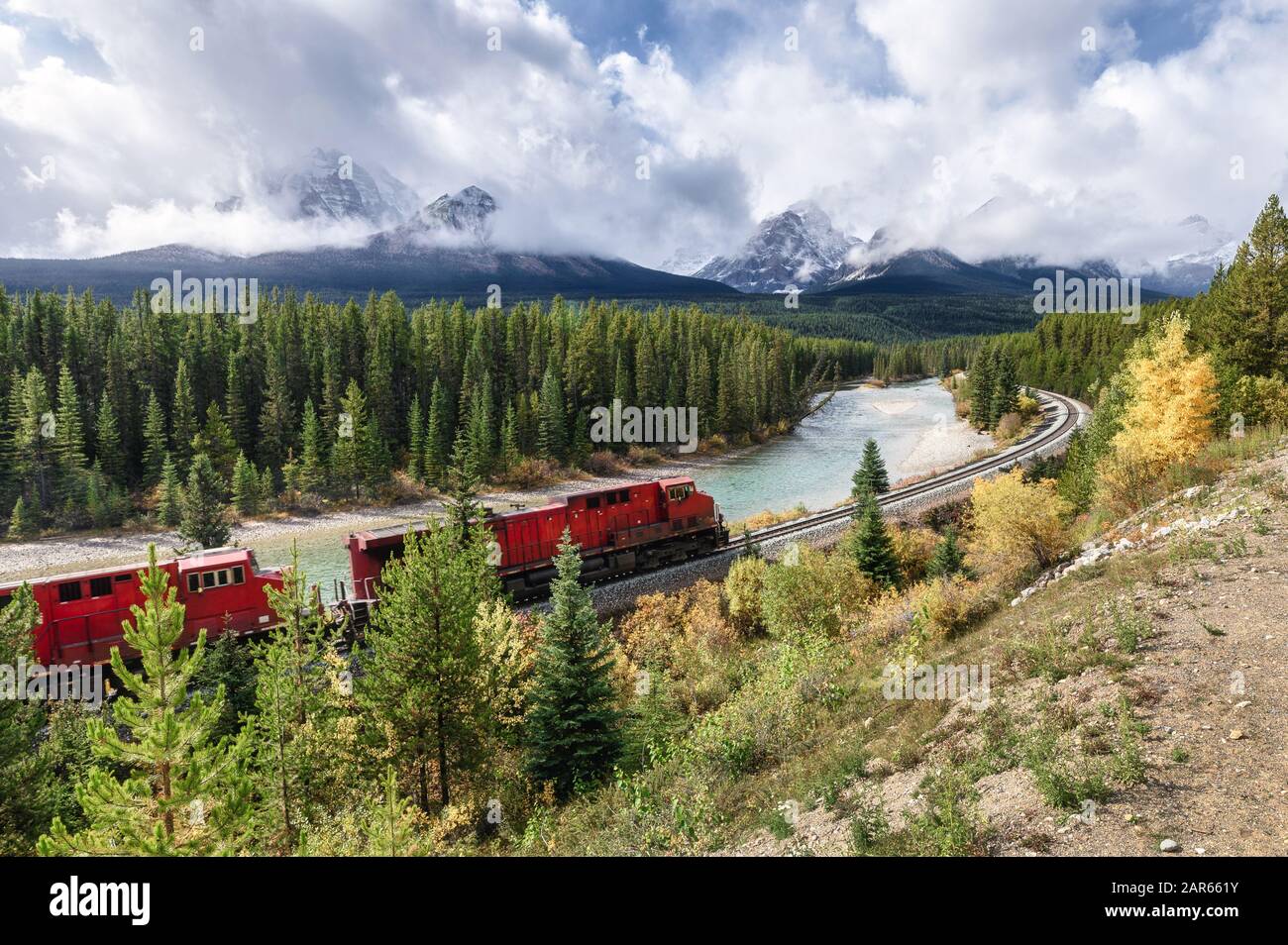 Red train long freight on railway passing in autumn valley and bow ...