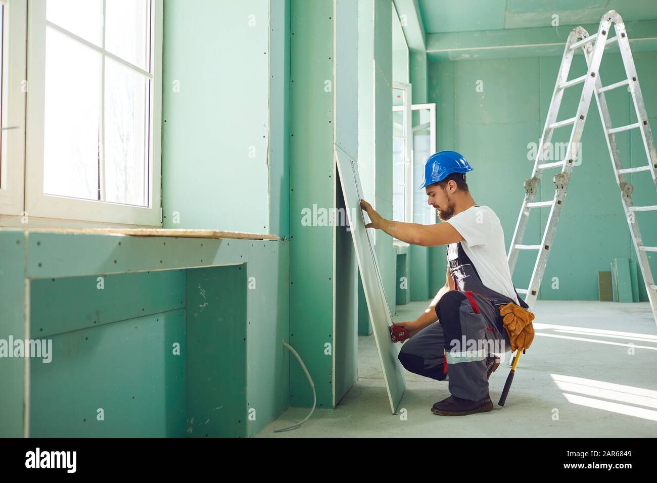 Worker builder installs plasterboard drywall at a construction Stock ...